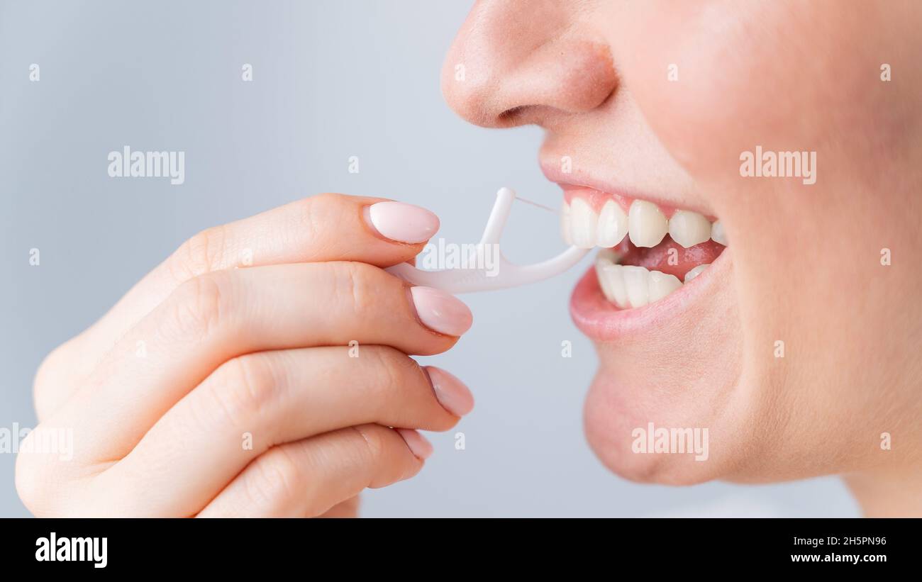Caucasian woman brushing teeth with toothpick with dental floss on ...