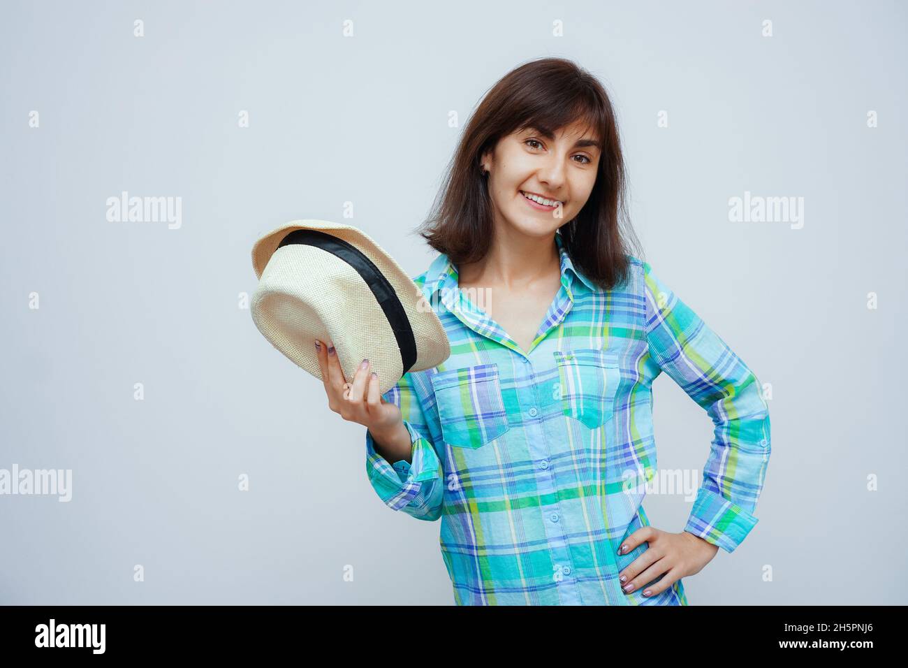 Young smiling brunet caucasian woman taking off hat isolated on gray ...