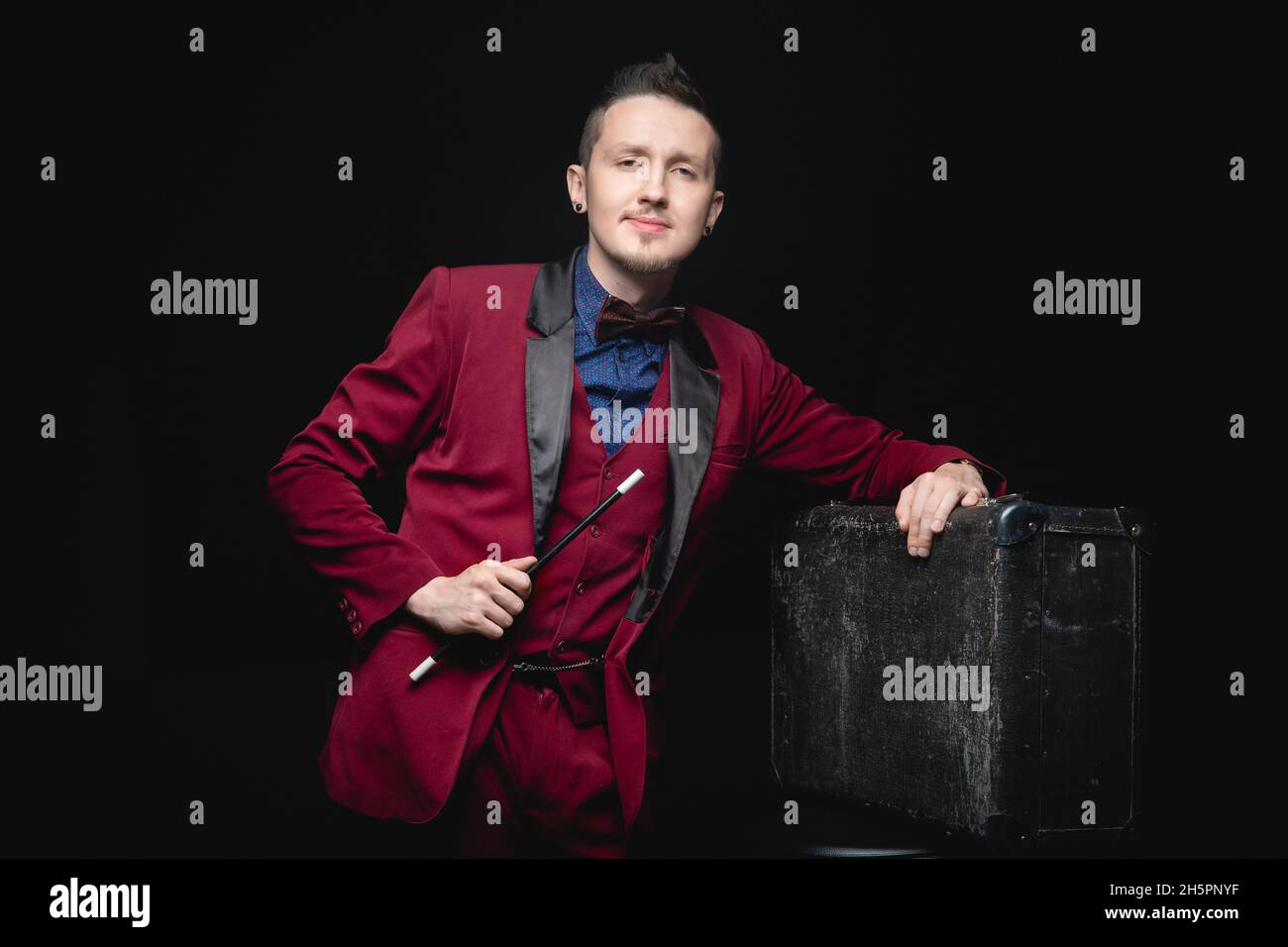 Magician man with magic wand and suitcase on black background Stock ...