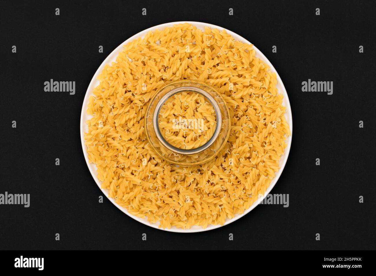 Uncooked Fusilli Pasta Lying on White Plate on Black Background. Raw ...