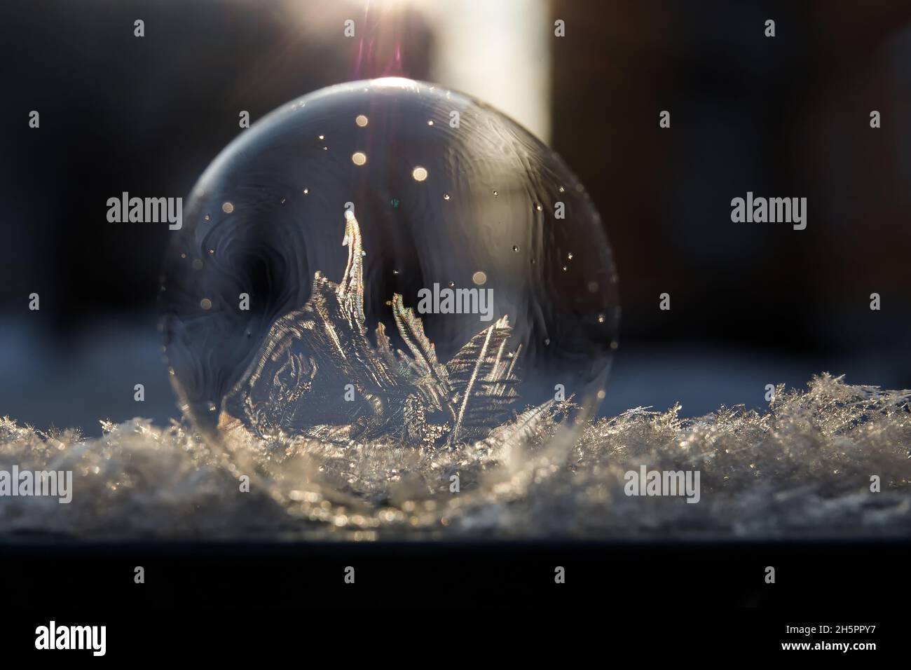 Frozen soap bubble with a beautiful pattern on the snow close-up on a ...