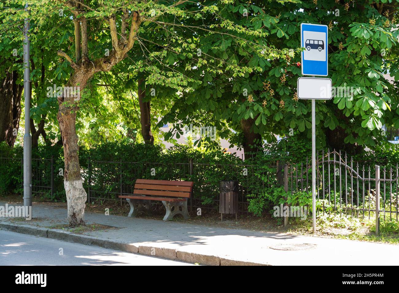 A bench near the bus stop with trees. An old bus parking lot with a ...