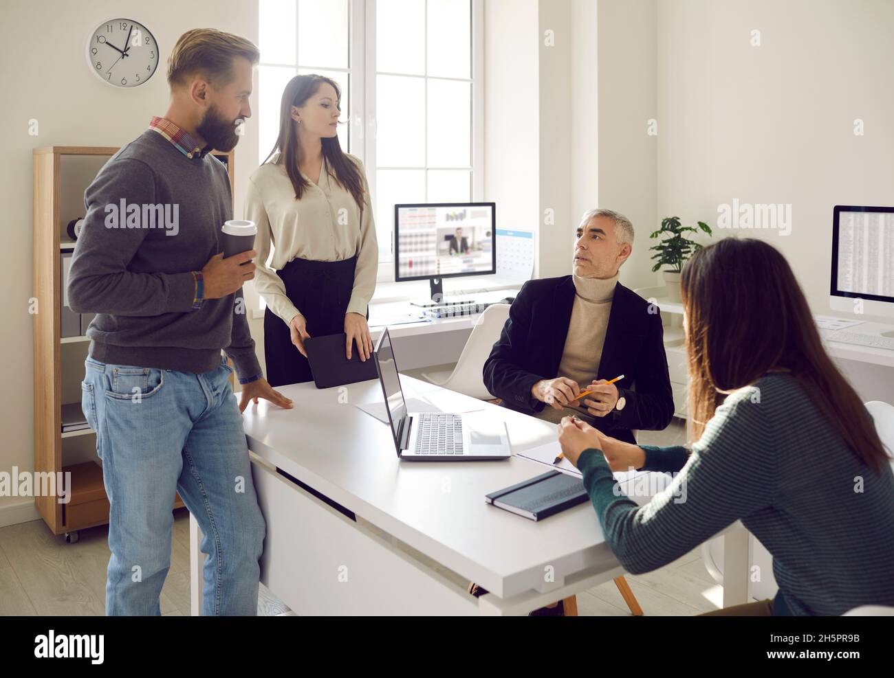 Group of staff in office discusses work issues and new ideas during ...