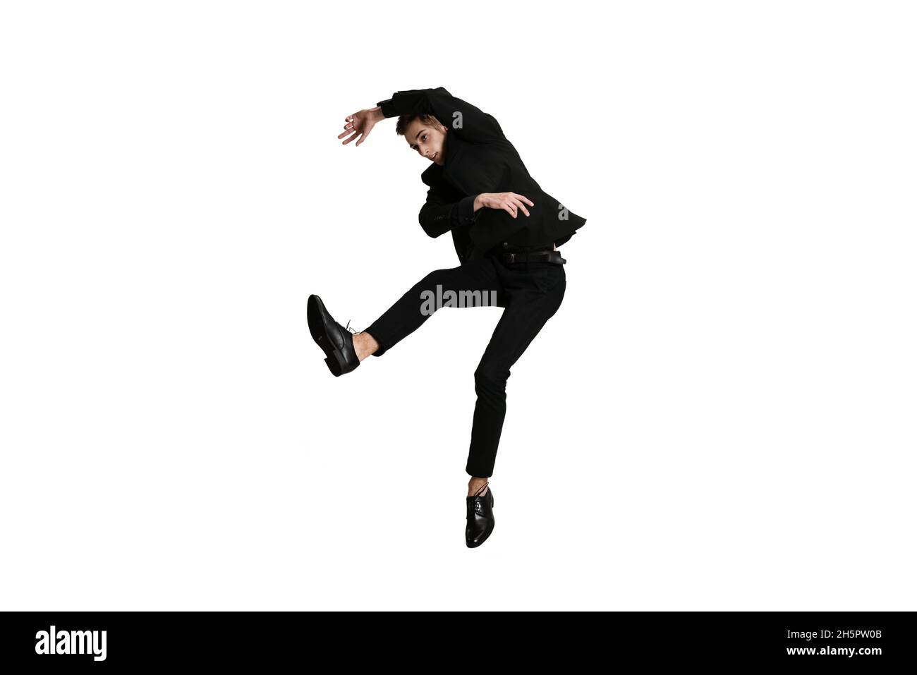 Dynamic portrait of young man in black business suit dancing isolated ...