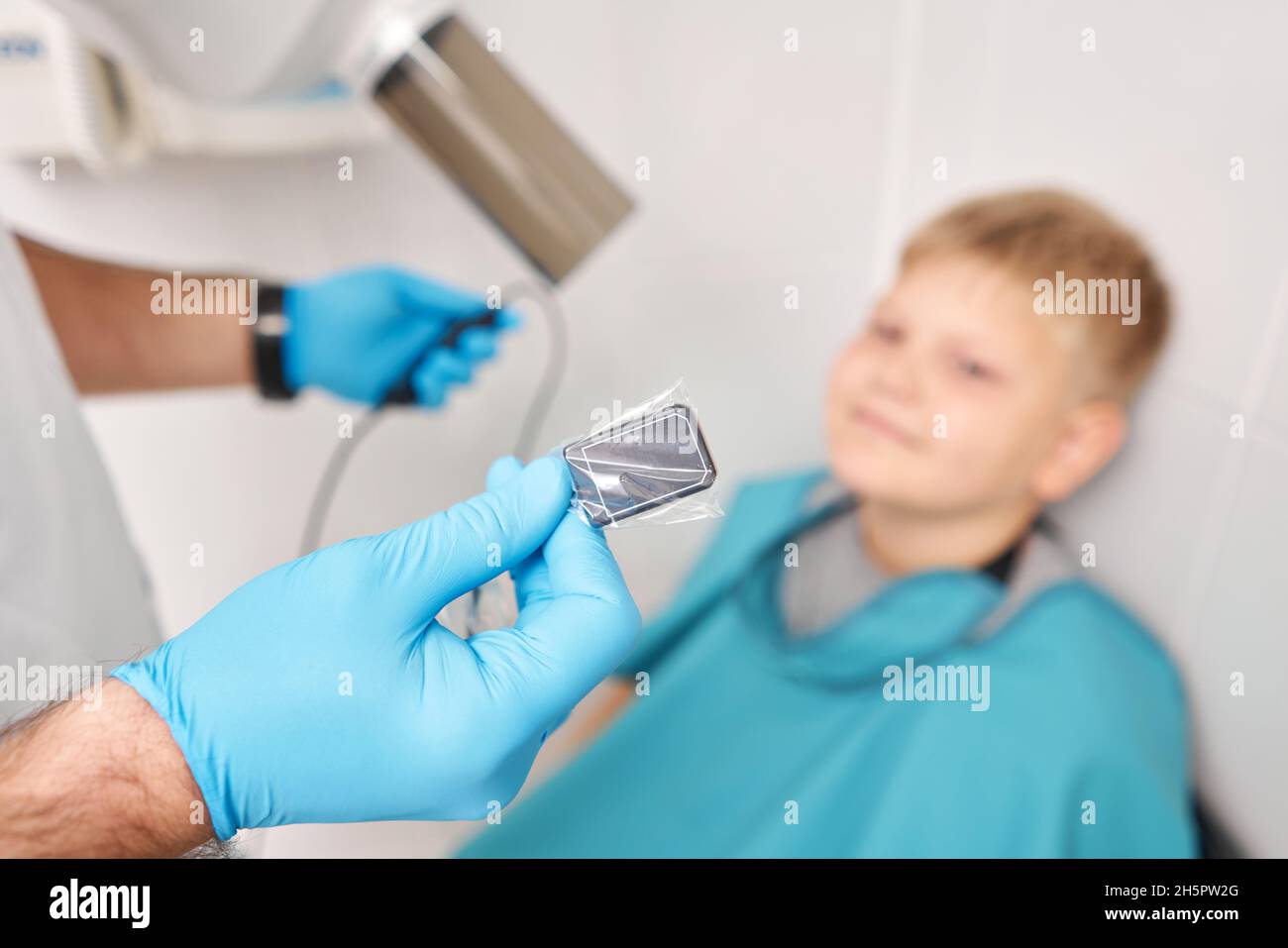 Radiographer taking teeth radiography to a boy using digital x-ray machine in pediatric dental ...