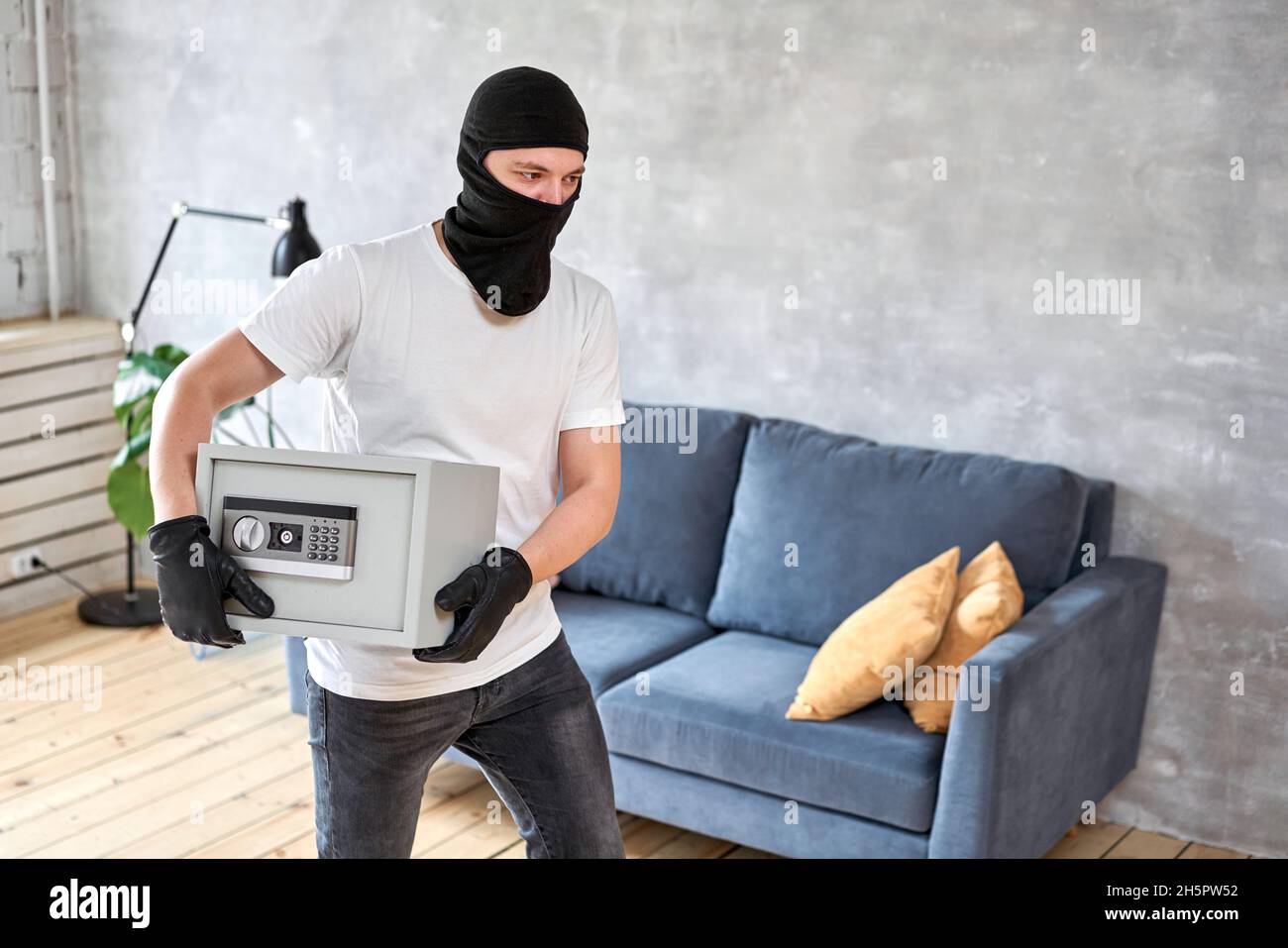 Thief with black mask stealing modern Metal safe with an electronic ...