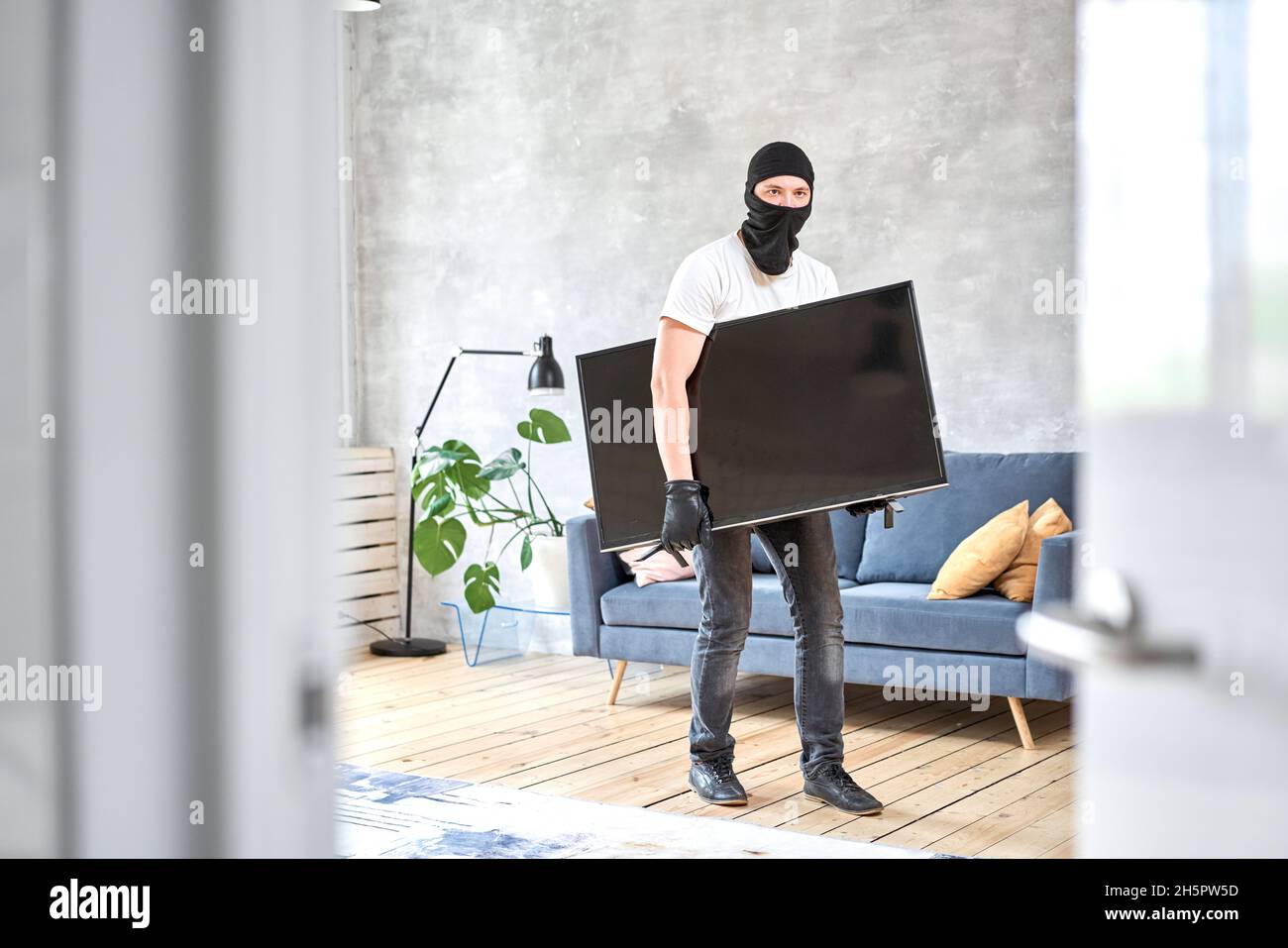 Thief with black balaclava stealing modern expensive television. Masked ...