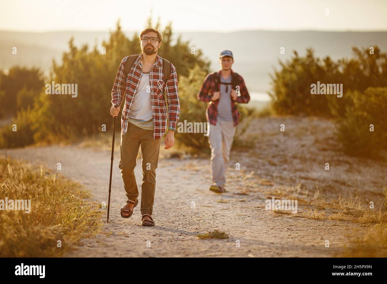 two men hikers enjoy a walk in nature, sunset time in summer. enjoying ...
