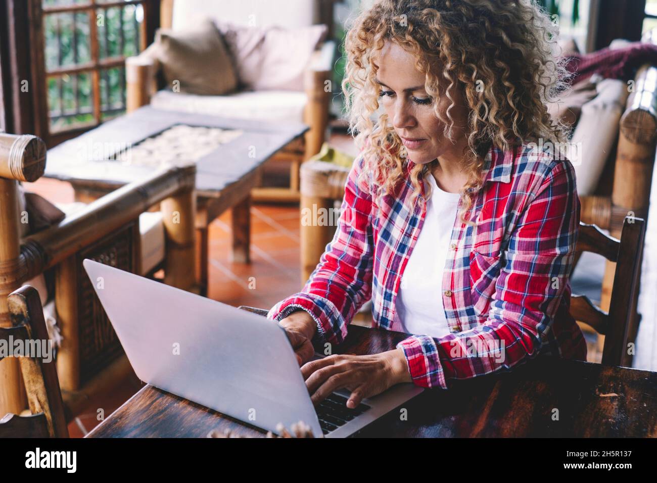 One adult woman at home working on laptop on the table. Modern hipster ...