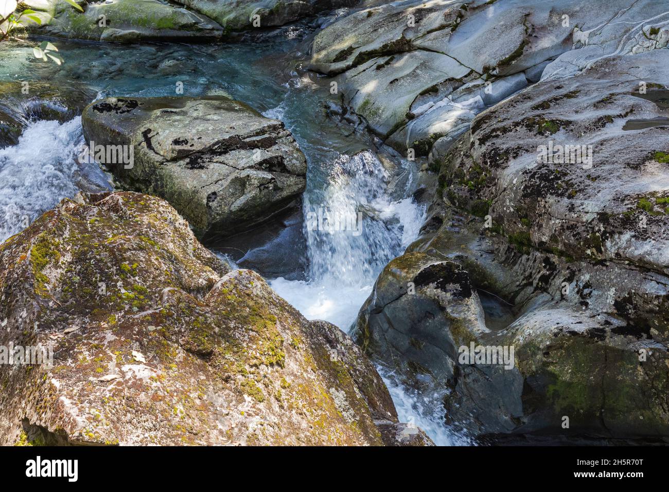 A stream disappearing into a funnel. New Zealand. Stream among stones ...