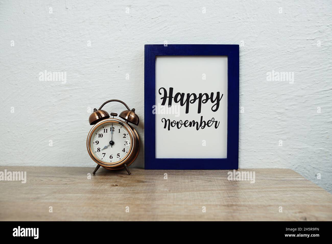 Happy November typography text and alarm clock on wooden table and ...