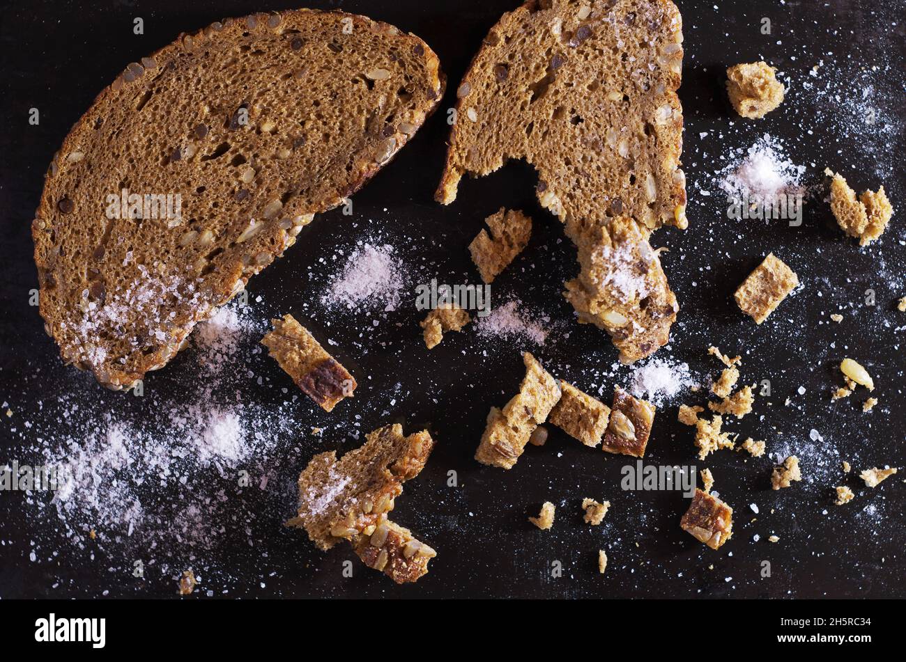 Pieces of bread with salt on old black metal as a background of food ...