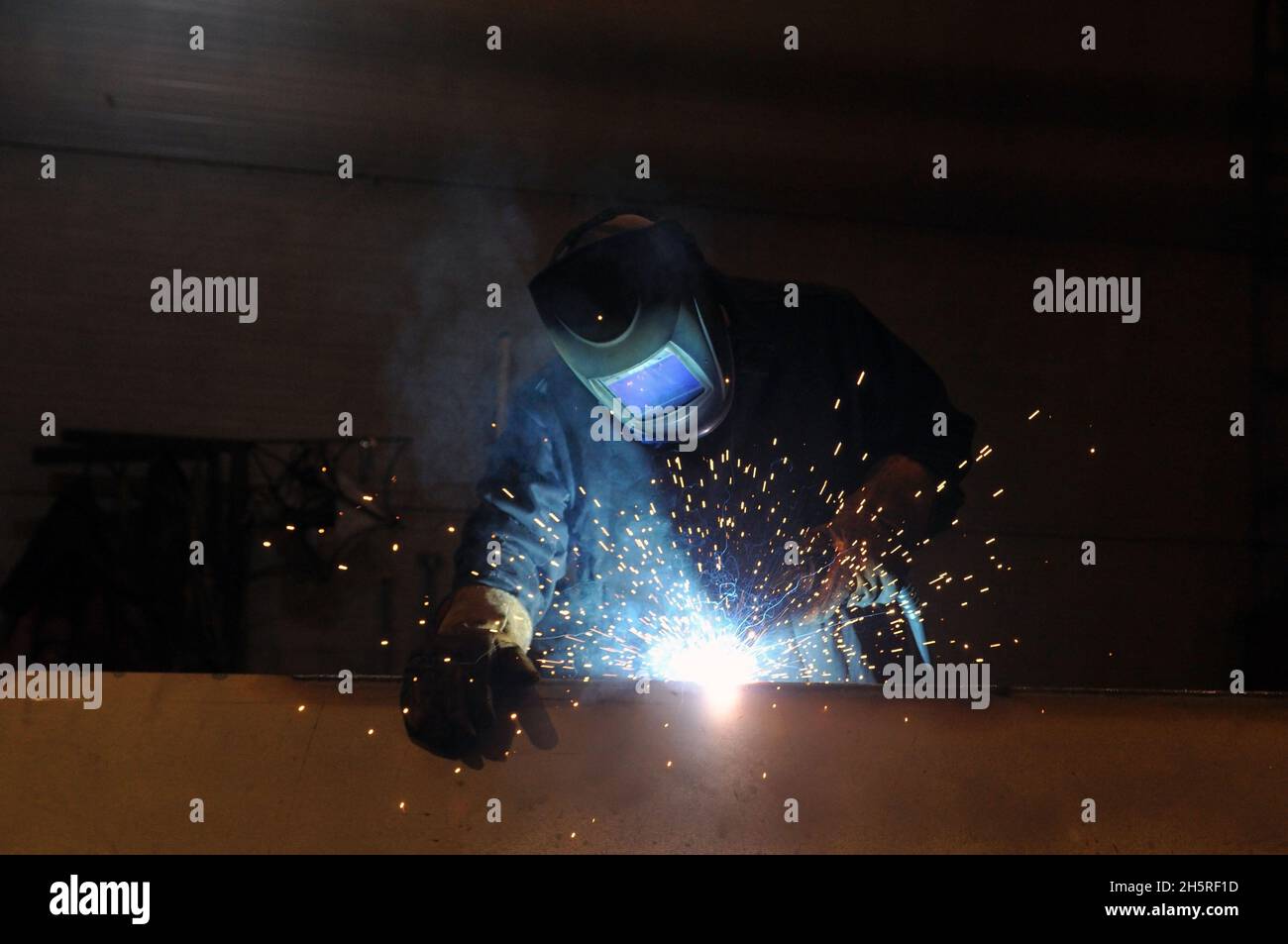 Electric welder at work. A worker welds metal structures at a factory ...