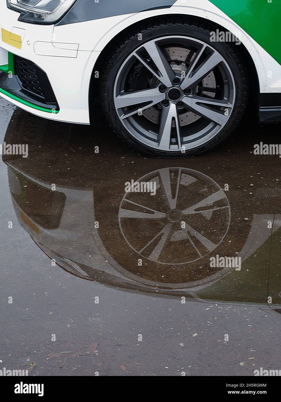 The left front wheel of a car is reflected in a puddle of water Stock ...