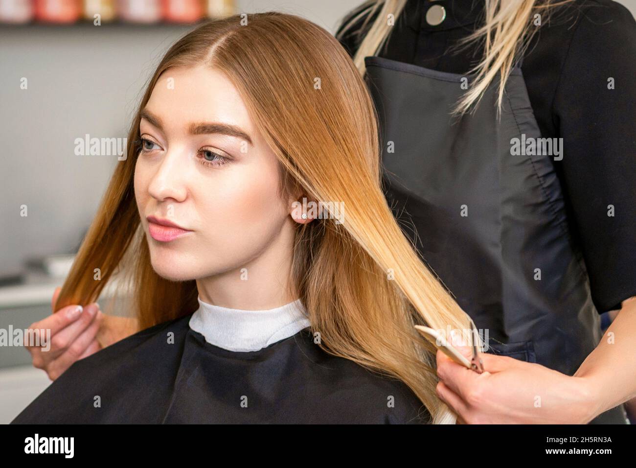 Hair stylist's hands doing professional hairstyling of female long hair ...