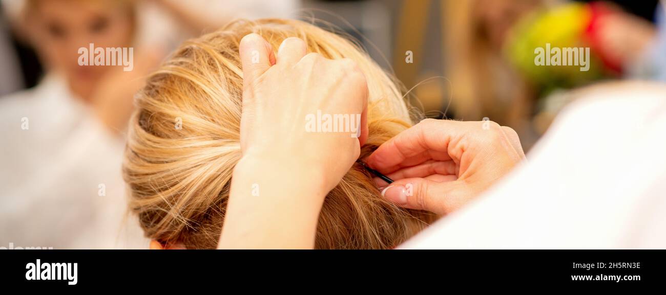 Hair stylist's hands doing professional hairstyling of female long hair ...