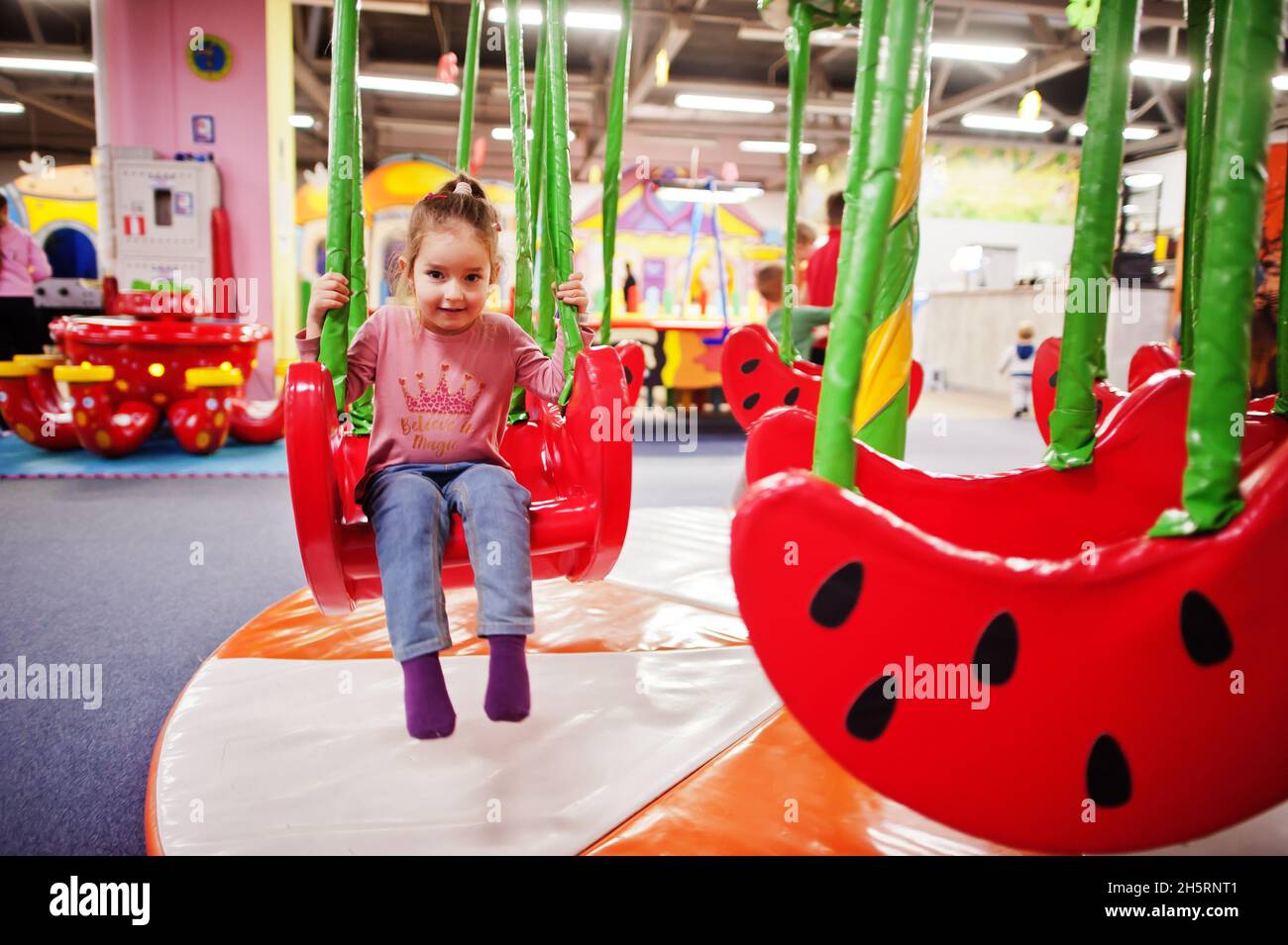 Cute baby girl swinging on swings in indoor play center Stock Photo - Alamy