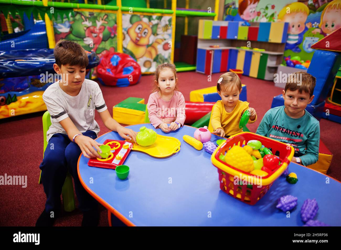 Four kids playing in indoor play center. Kindergarten or preschool play ...