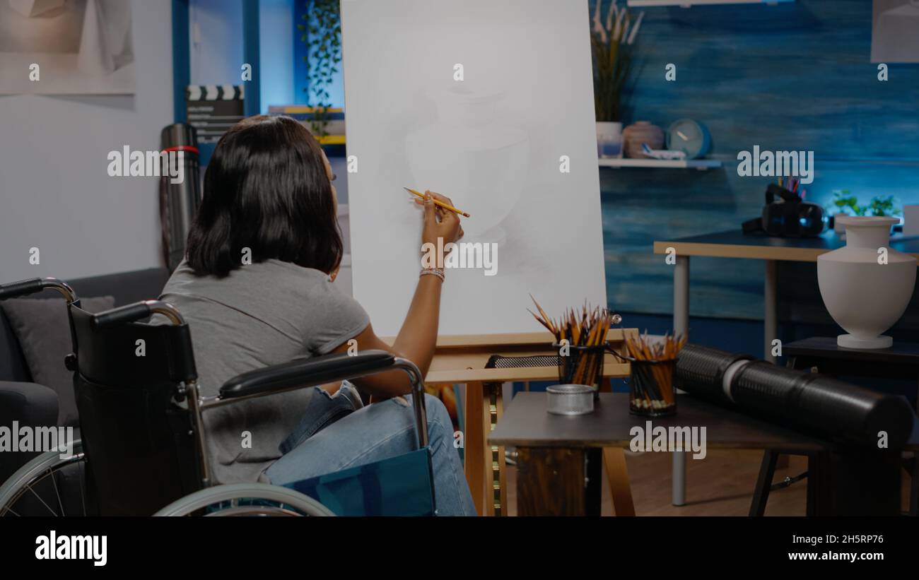 Black artist with handicap using pencil on canvas for authentic vase ...