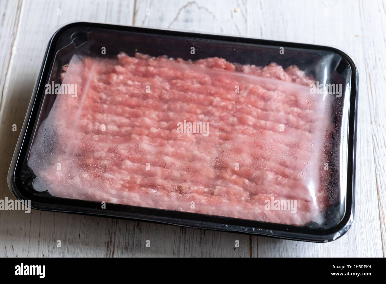 Minced meat in plastic packaging on a light wooden background Stock ...