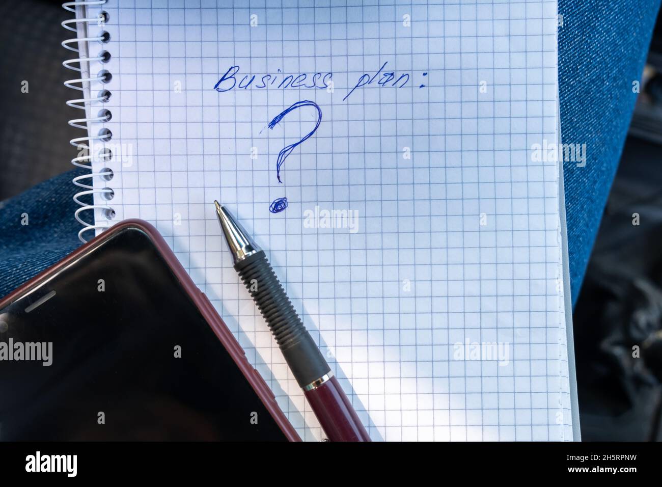 Business plan and question mark written on a notebook. Reflections on ...