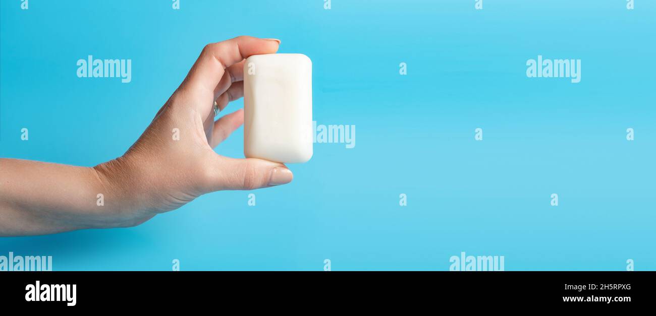 Global Handwashing Day. A bar of soap in a female hand on a blue ...