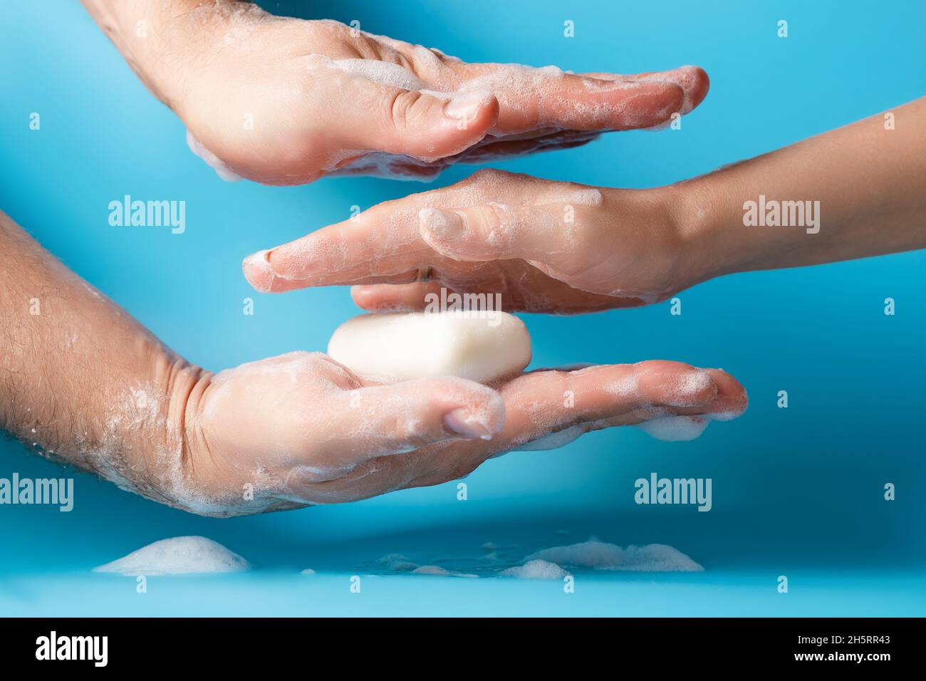 Male and female hand in soapy blue background. Hand washing, personal ...