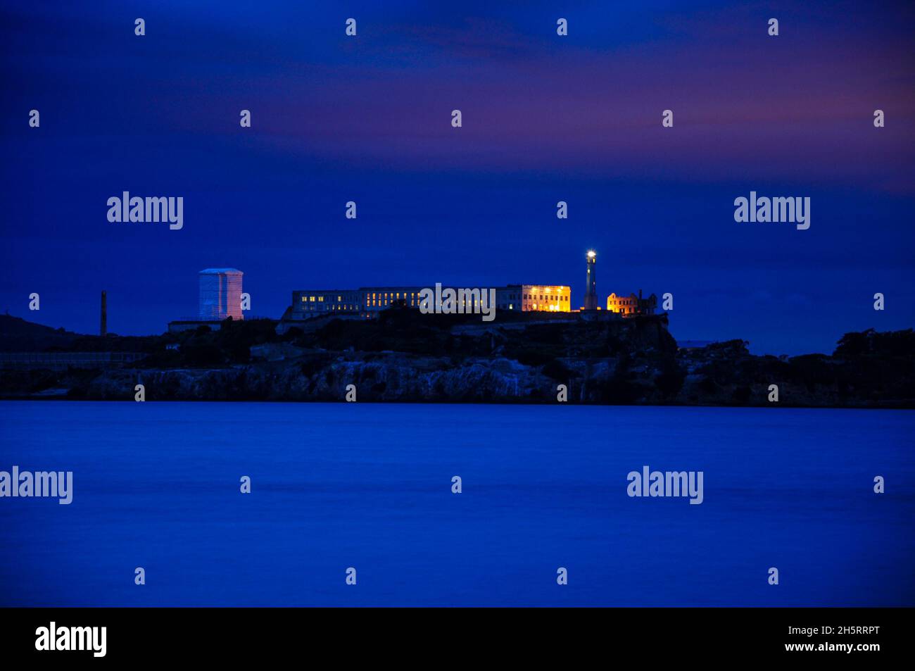 Alcatraz Island illuminated and seen in the distance, at sunset, in San ...