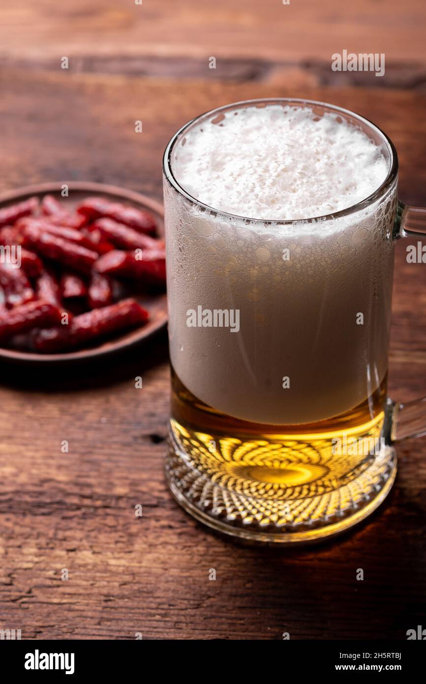 Glass of beer and snacks- dried sausages on a wooden background Stock ...