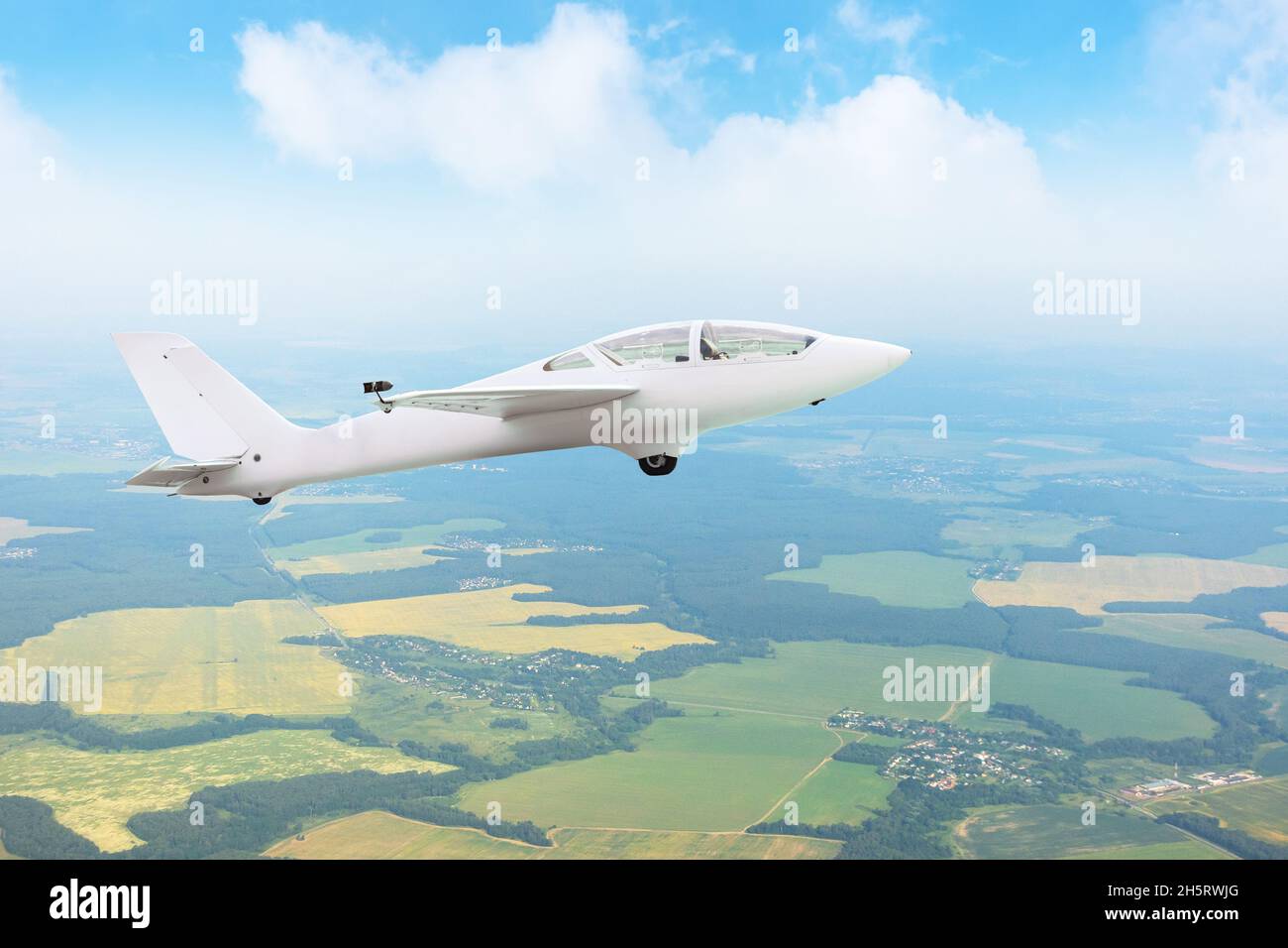Glider flying high in the sky over fields and forests, aerial view ...