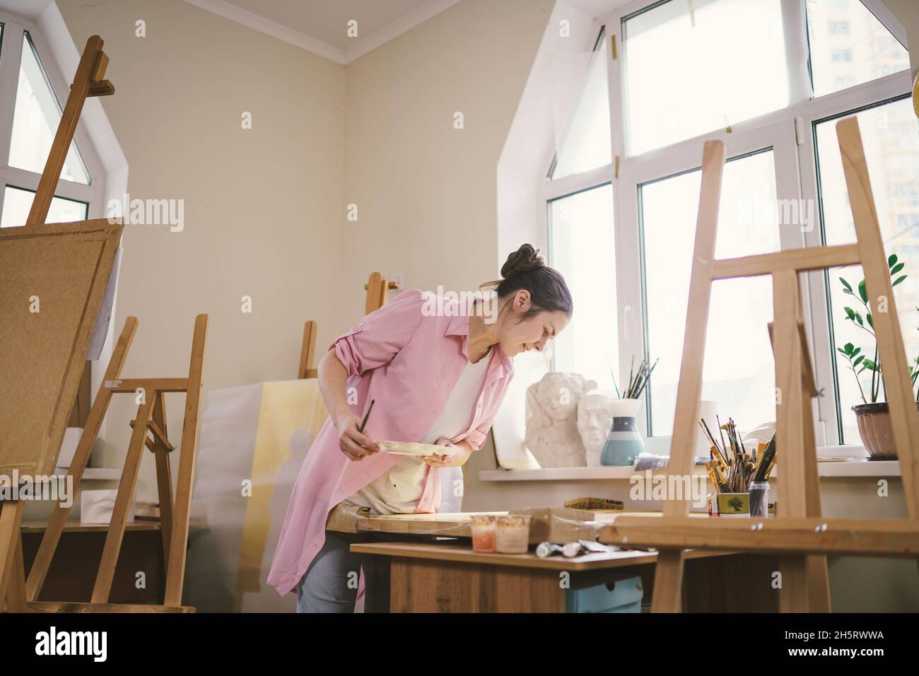 Female artist working in studio. Creative workspace, painting class ...