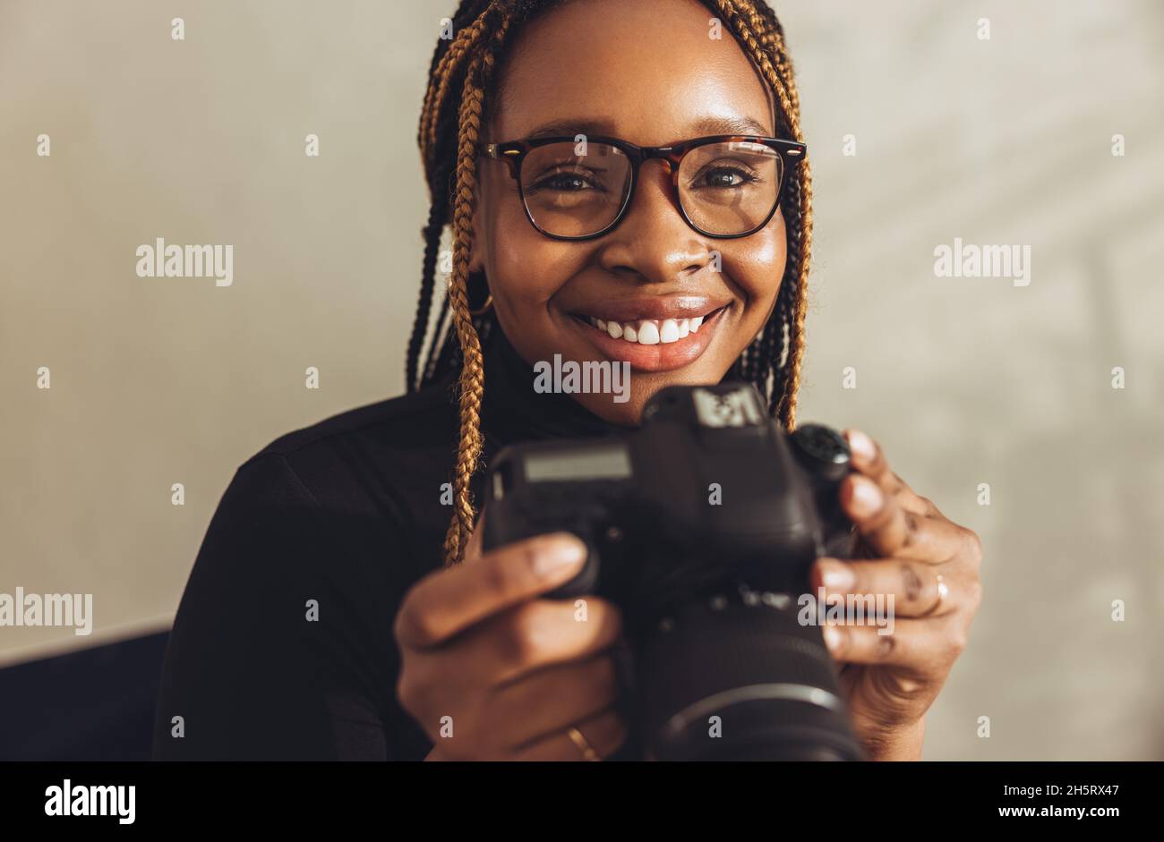 I have a passion for photography. Happy female photographer smiling cheerfully while holding a ...