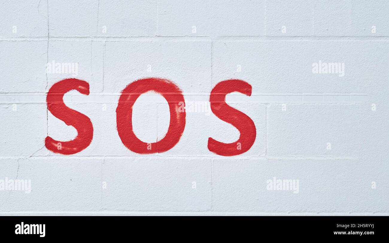 Image of the universal relief word sos painted in red on a white wall ...