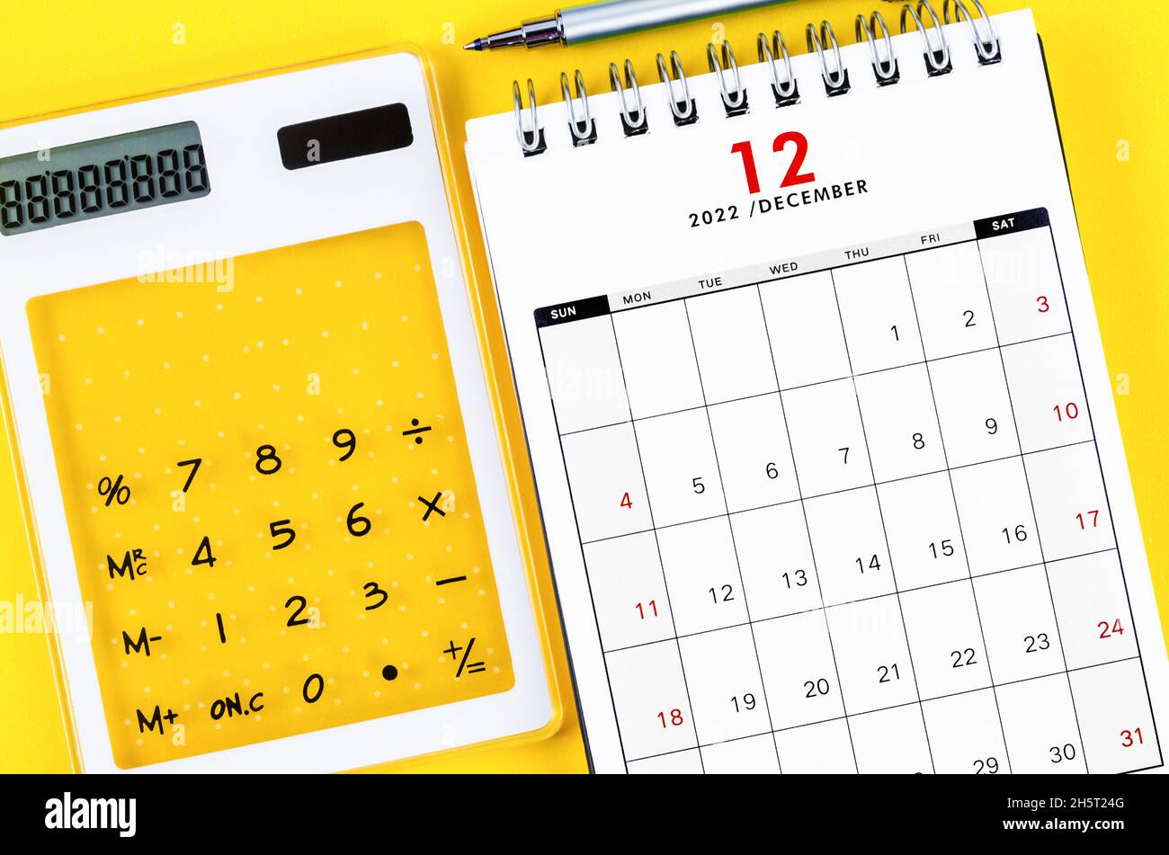 The December 2022 desk calendar with calculator and pen on yellow ...
