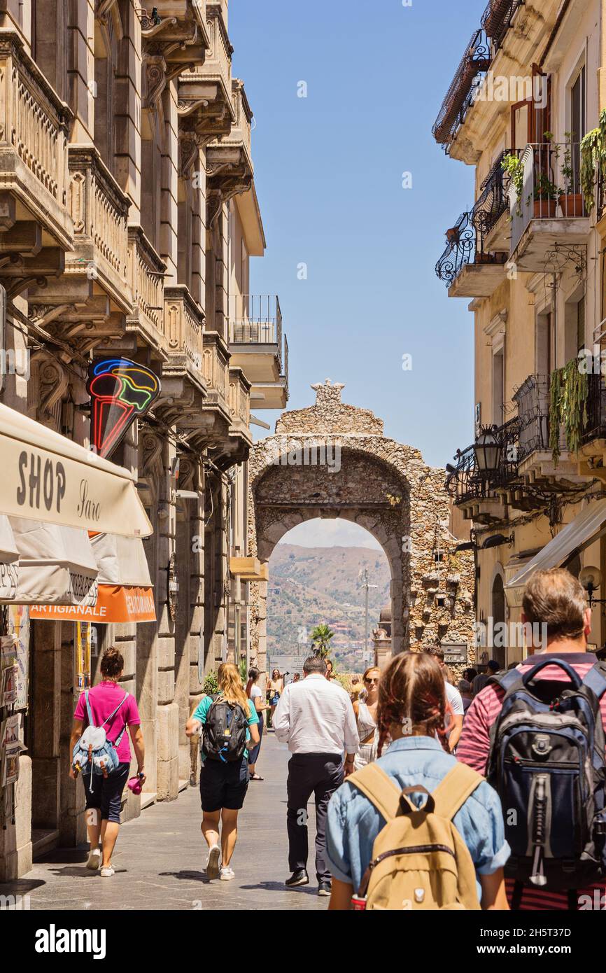 Rear View of tourists walking along ancient streets of Taormina Stock ...