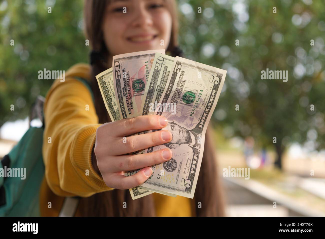 A teenage girl shows a lot of dollar bills and smiles Stock Photo - Alamy