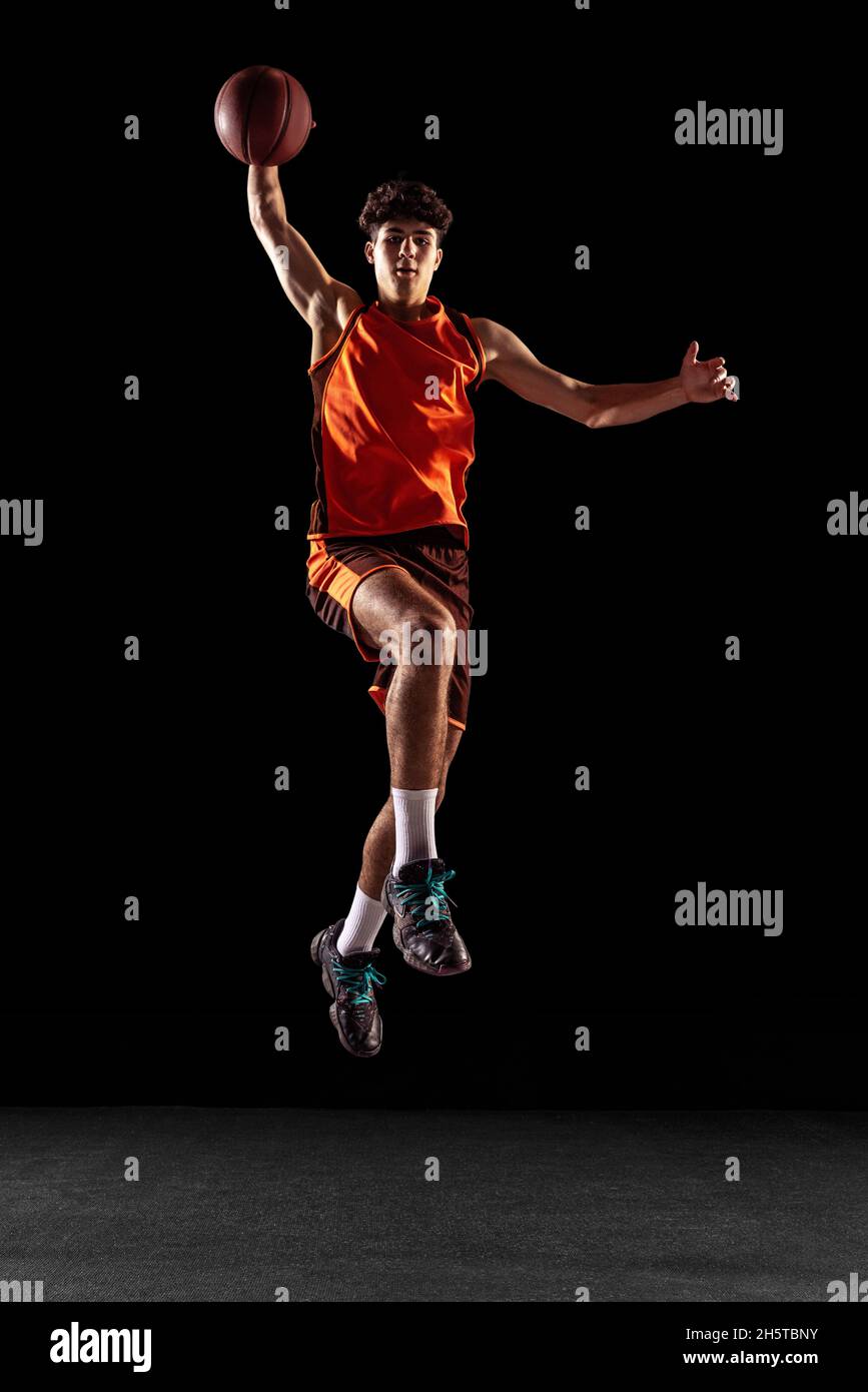 Full length portrait of basketball player training isolated on dark ...