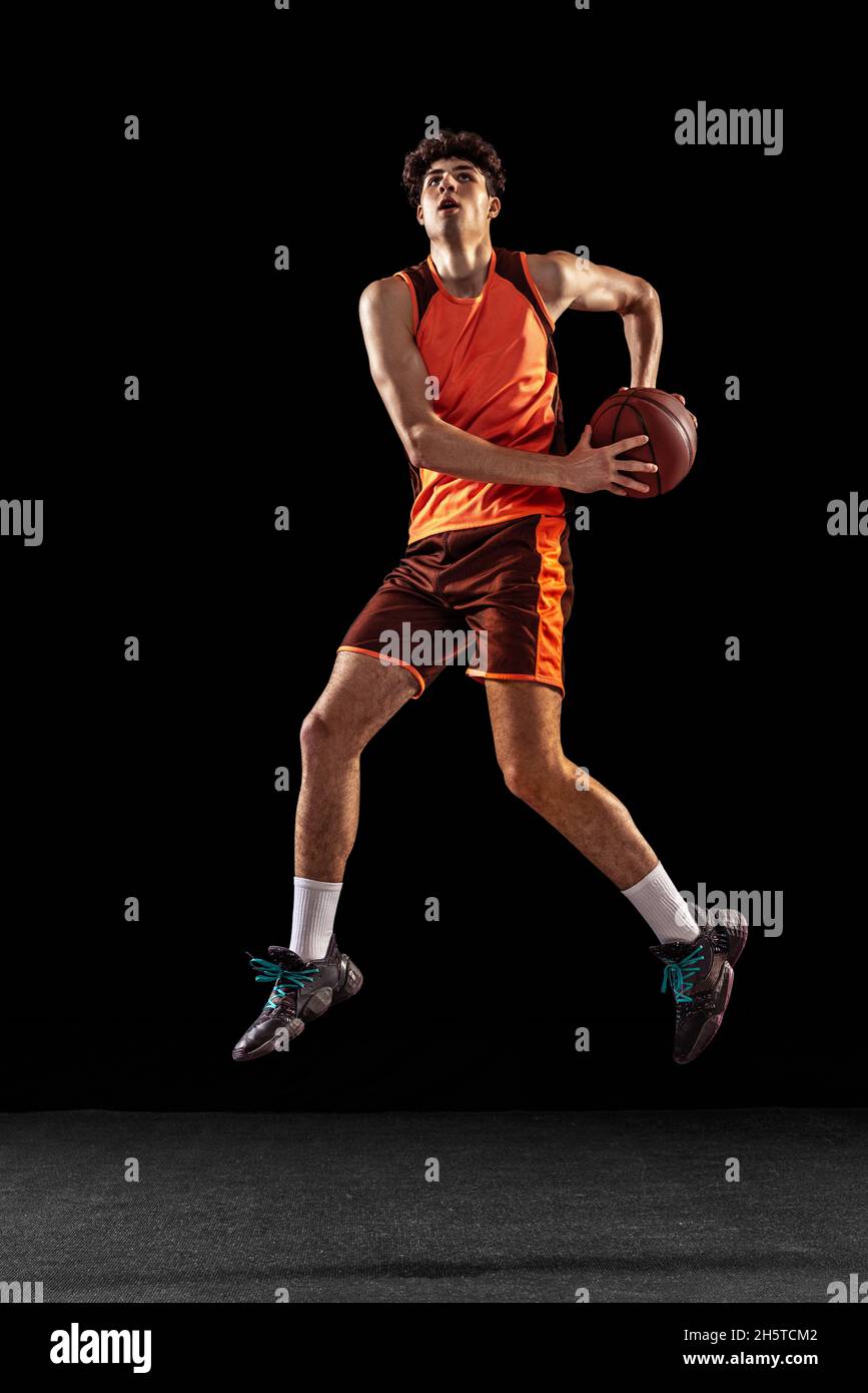 Full length portrait of basketball player training isolated on dark ...