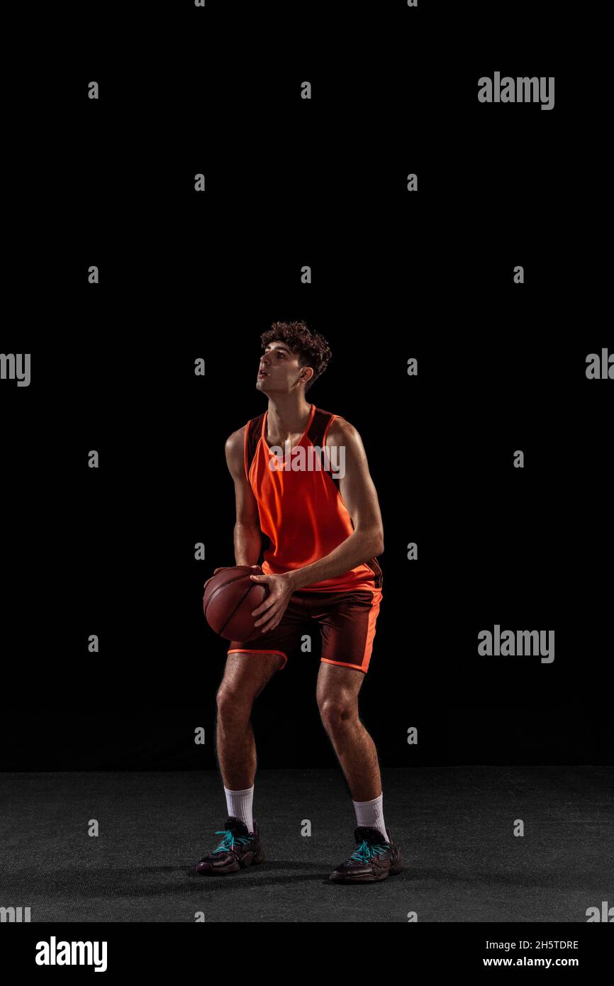 Full length portrait of basketball player training isolated on dark ...