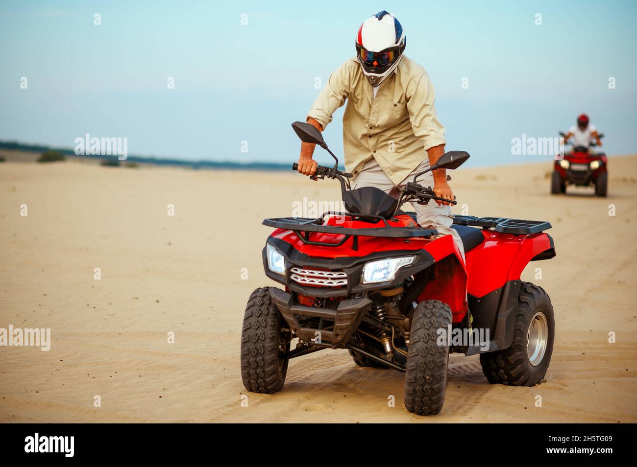 Man poses on atv, downhill riding in desert sands Stock Photo - Alamy
