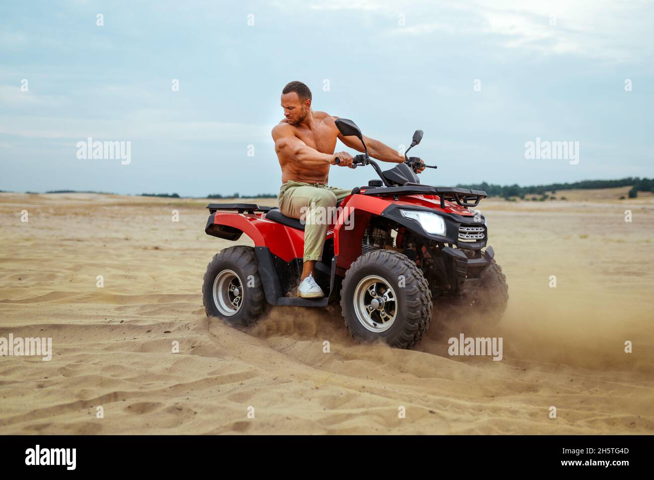 Brutal man poses on atv in desert sands, quadbike Stock Photo - Alamy