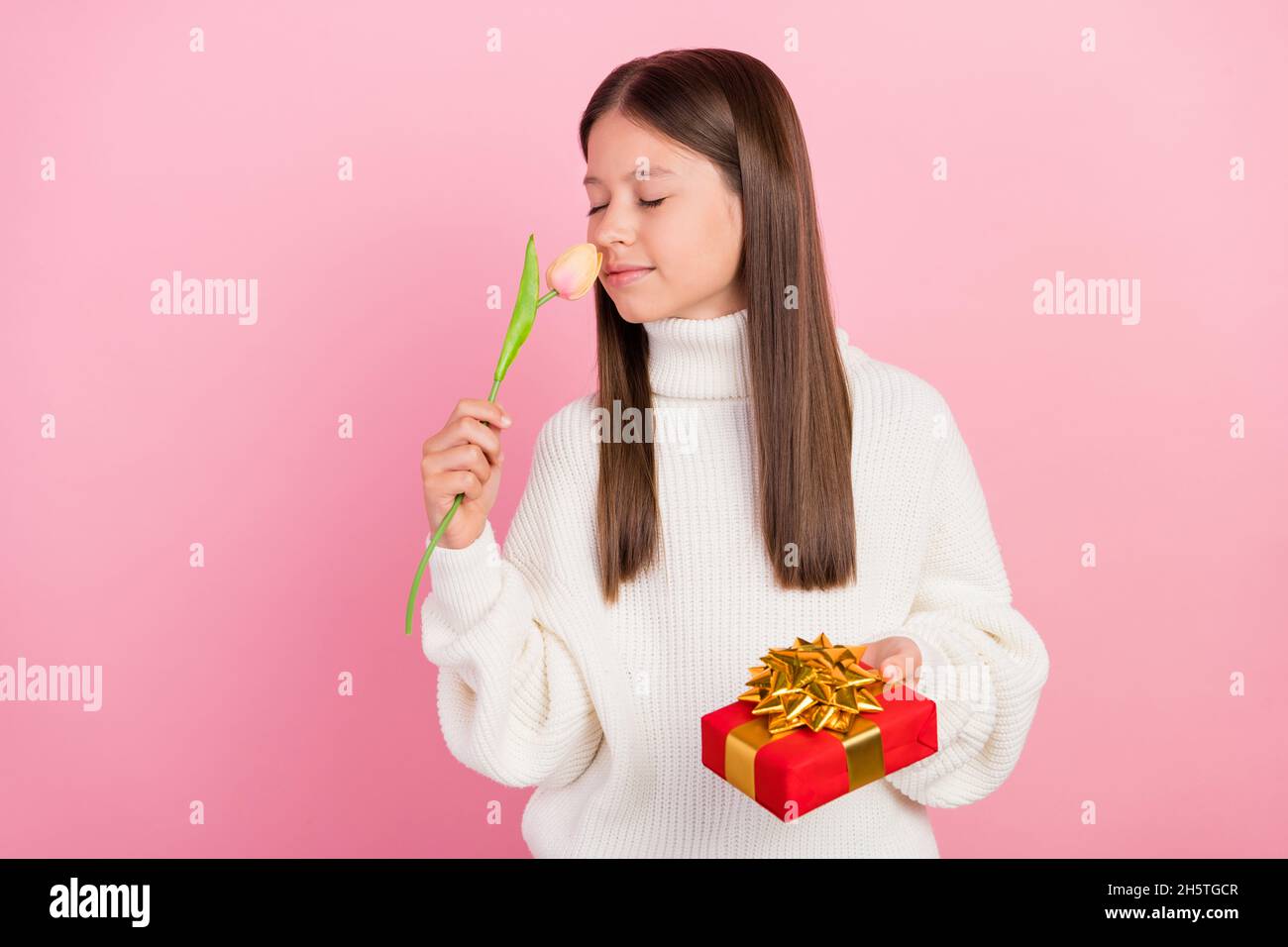 Photo of funny charming student girl wear white sweater smiling holding gift enjoying tulip ...