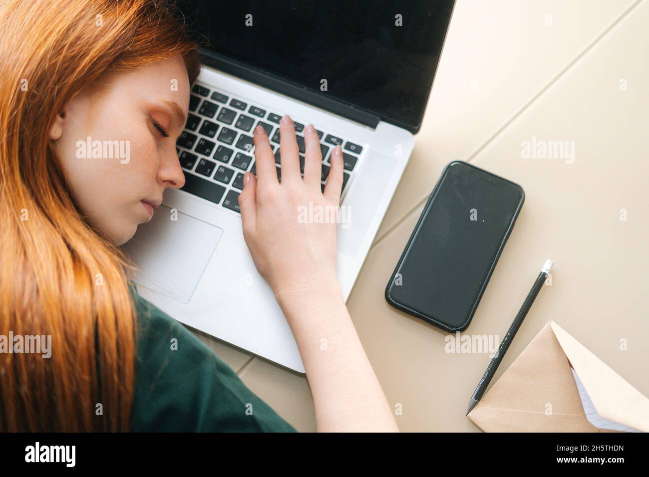 Close-up top view of overworked young woman sleeping on laptop keyboard ...