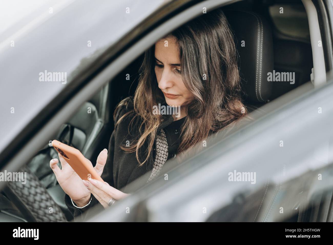 asian or mixed race woman sitting in a car and texting to a friend on a ...