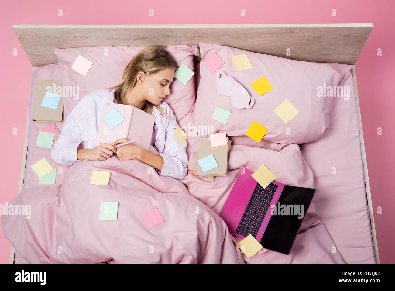Top view of woman with notebook sleeping near laptop, books and sticky ...