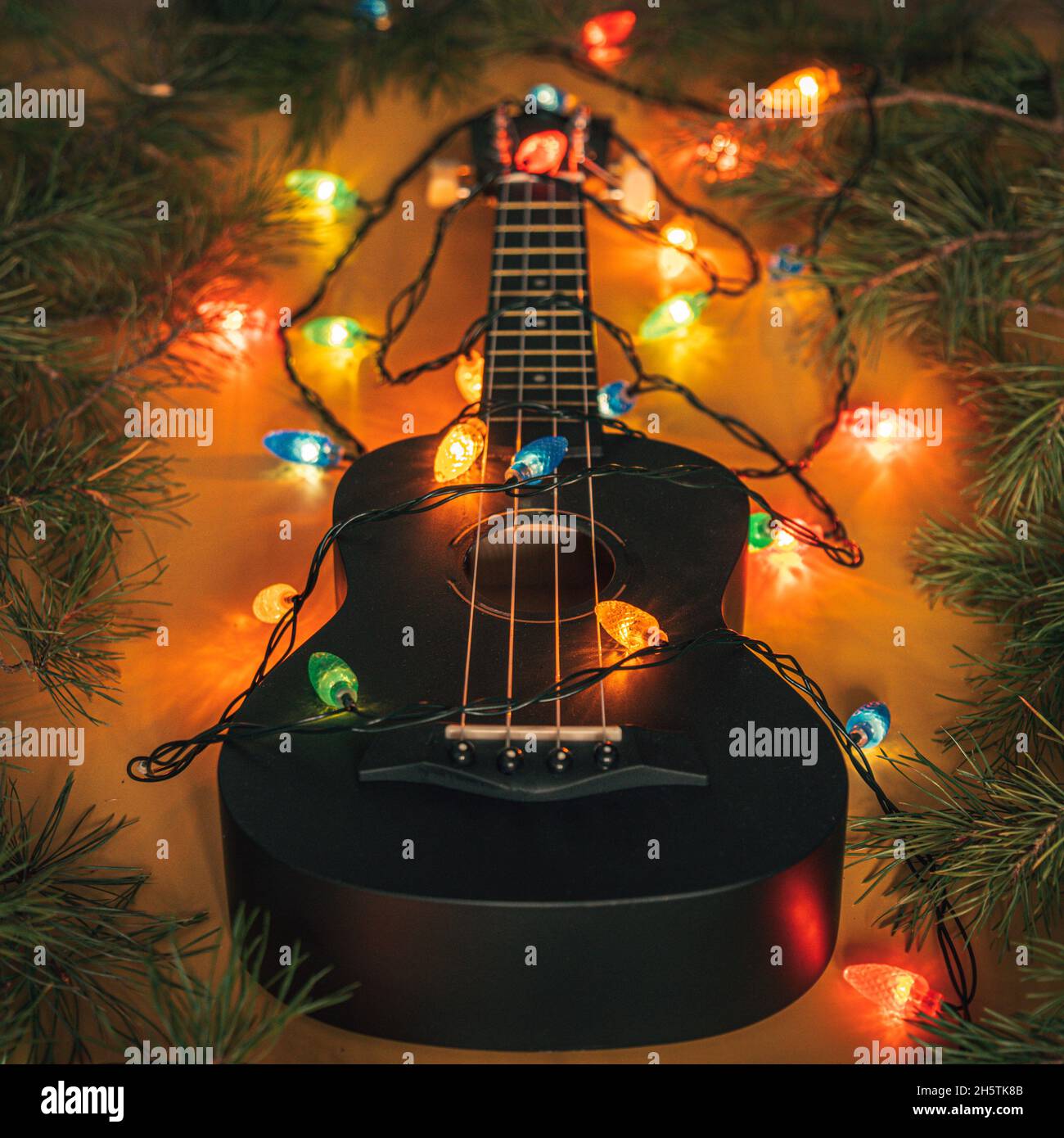 black ukulele guitar and christmas decorations on the dark background ...
