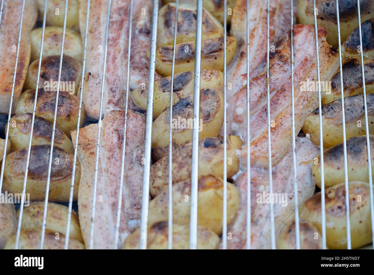 Grill potatoes and meat on wire rack closeup Stock Photo - Alamy