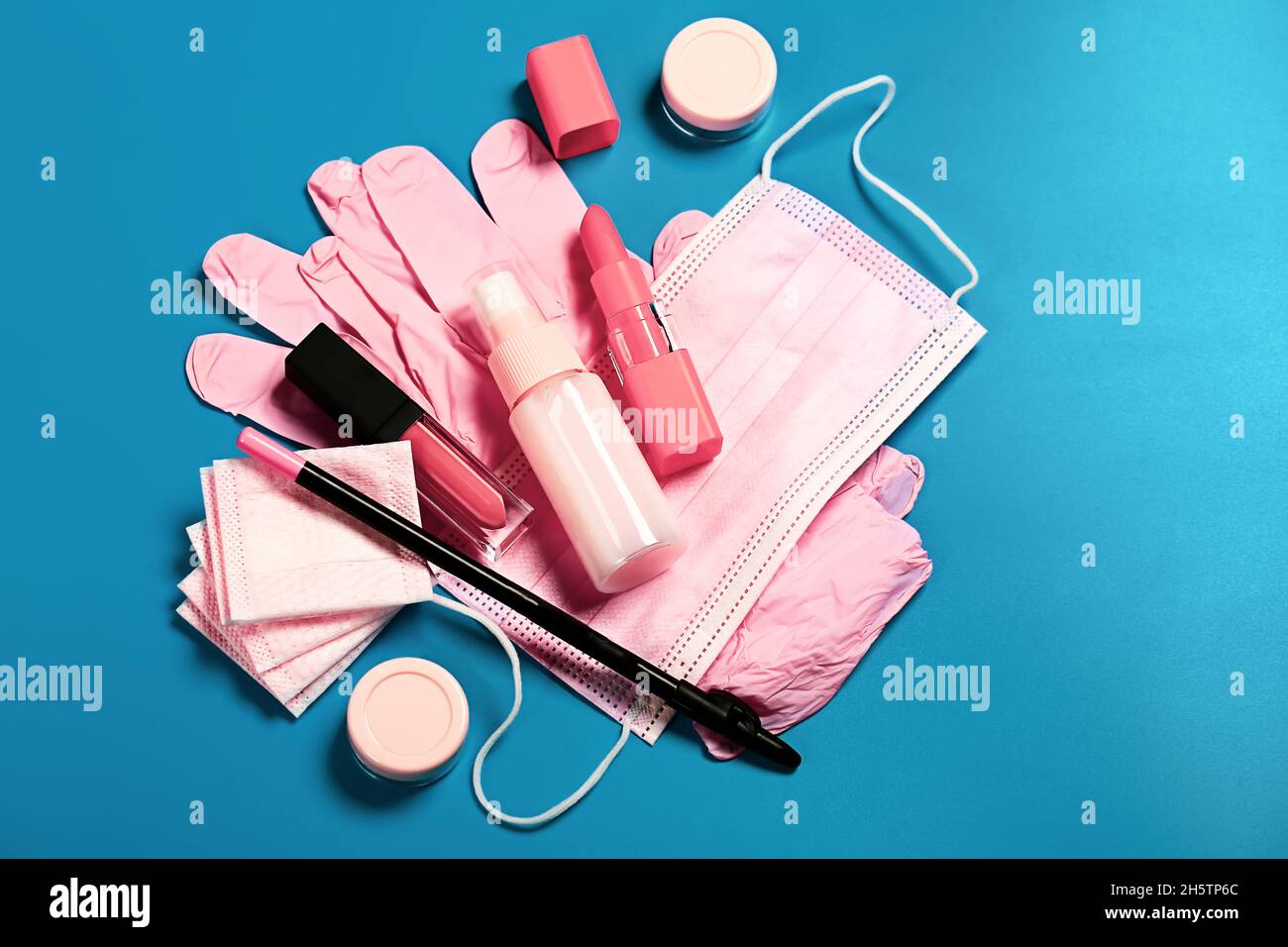 female protective travel cosmetic bag set. Pink mask, gloves, sanitizer, lip gel, pencil and ...
