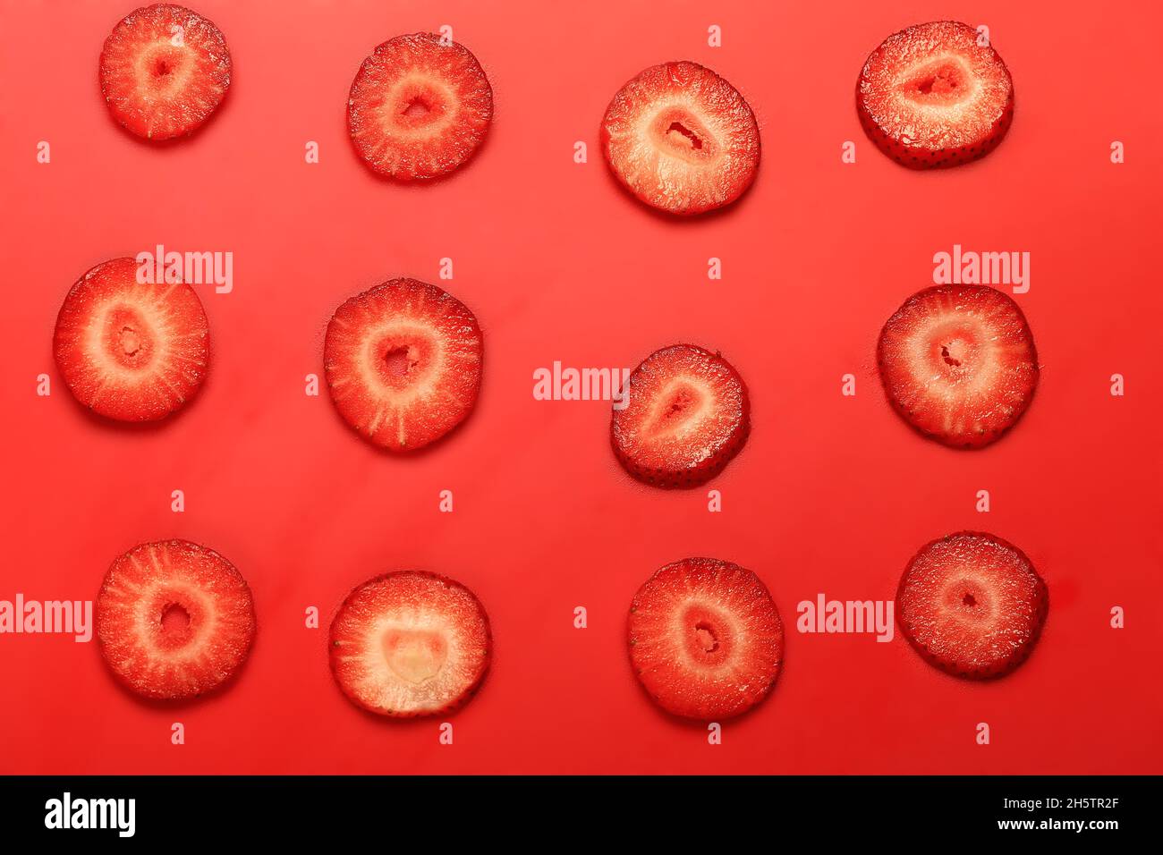 pattern of cut strawberries on a red background Stock Photo - Alamy