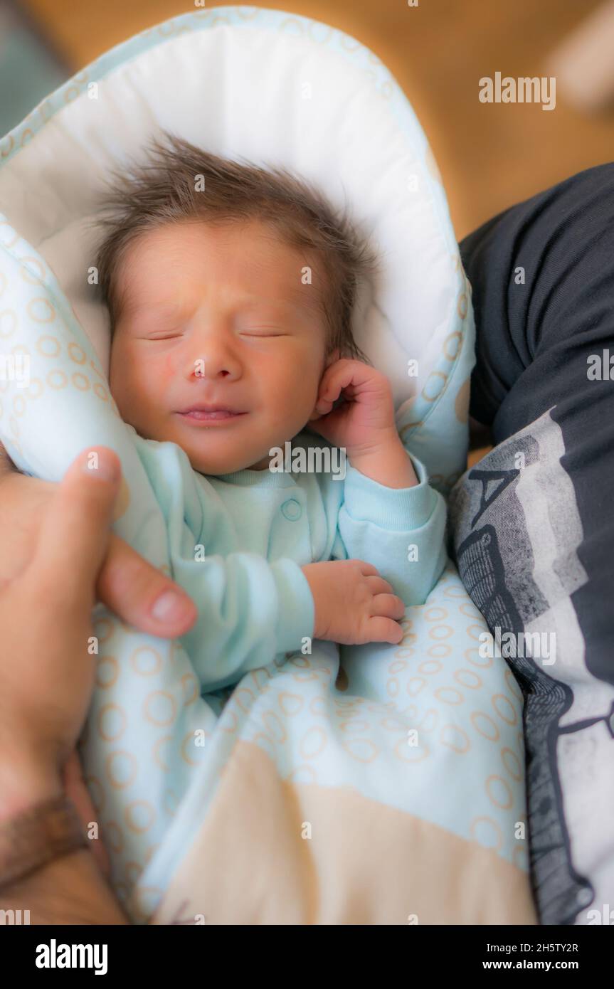 Vertical shot of a cute little Polish baby sleeping on father's arms ...